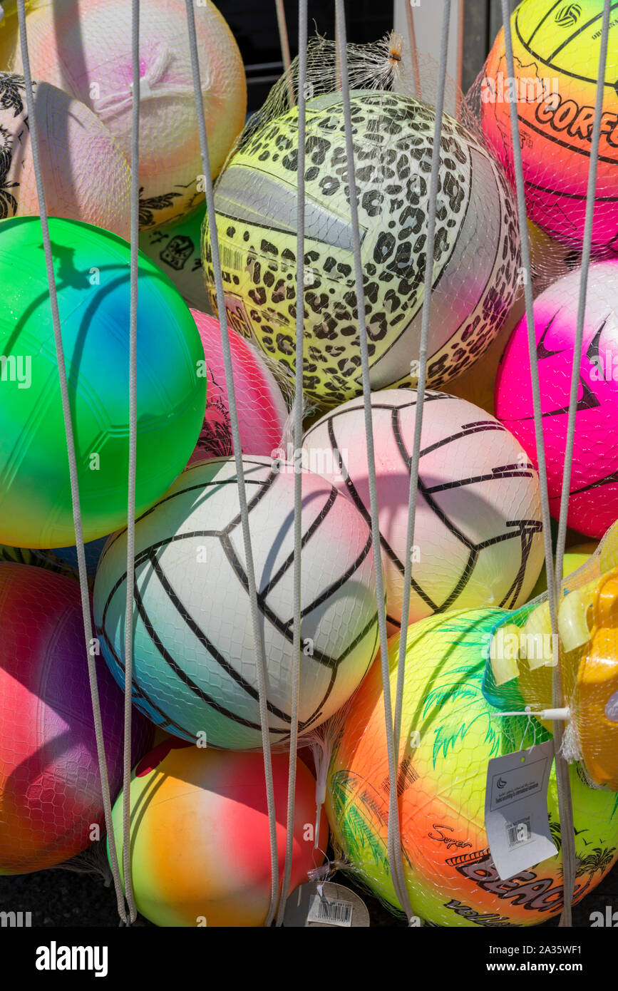 brightly coloured footballs made from plastic at a seaside shop for use ...