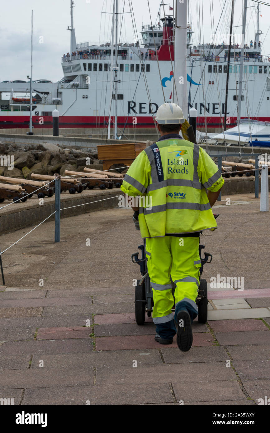 A stree cleaner pushing a barrow with brushes and brooms cleaning the ...