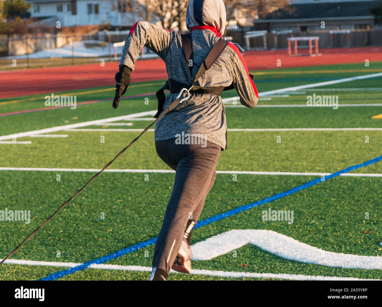 A high school track and field athlete is wearing a harness to pull a ...