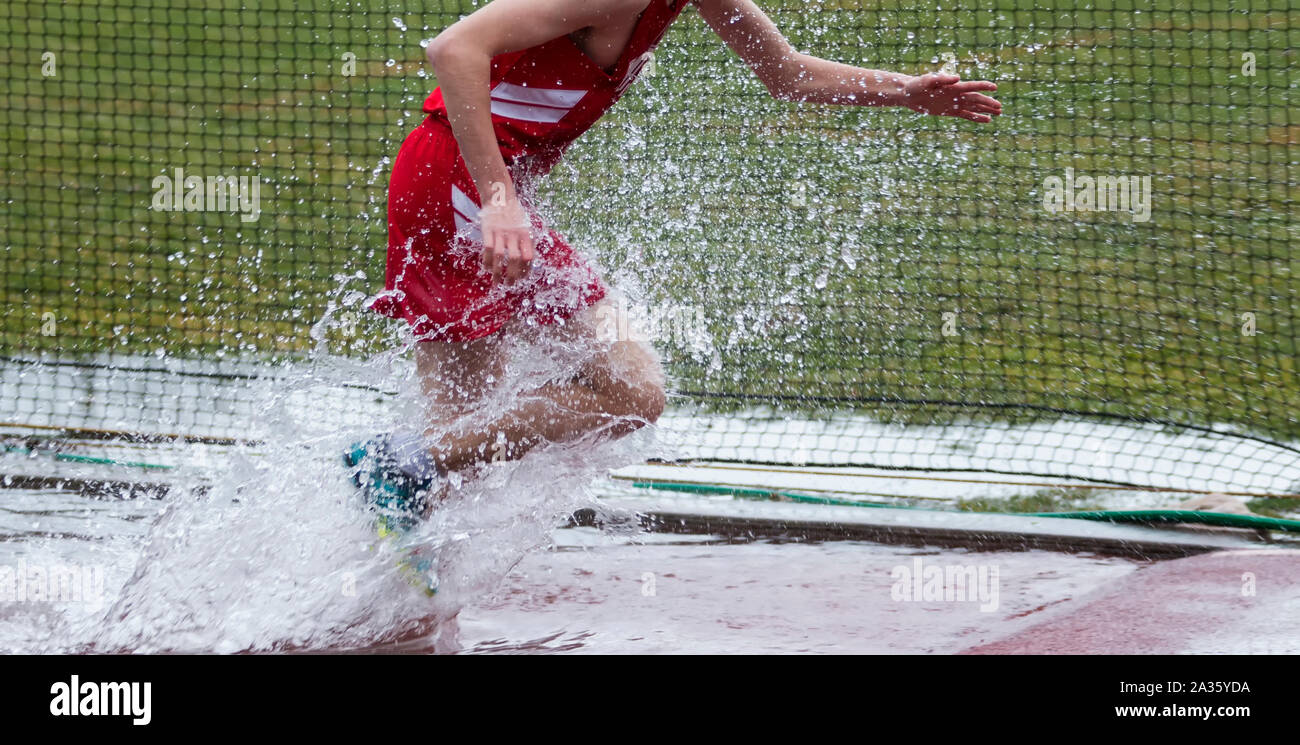 A high school track and field runner competing in the steeplechase ...