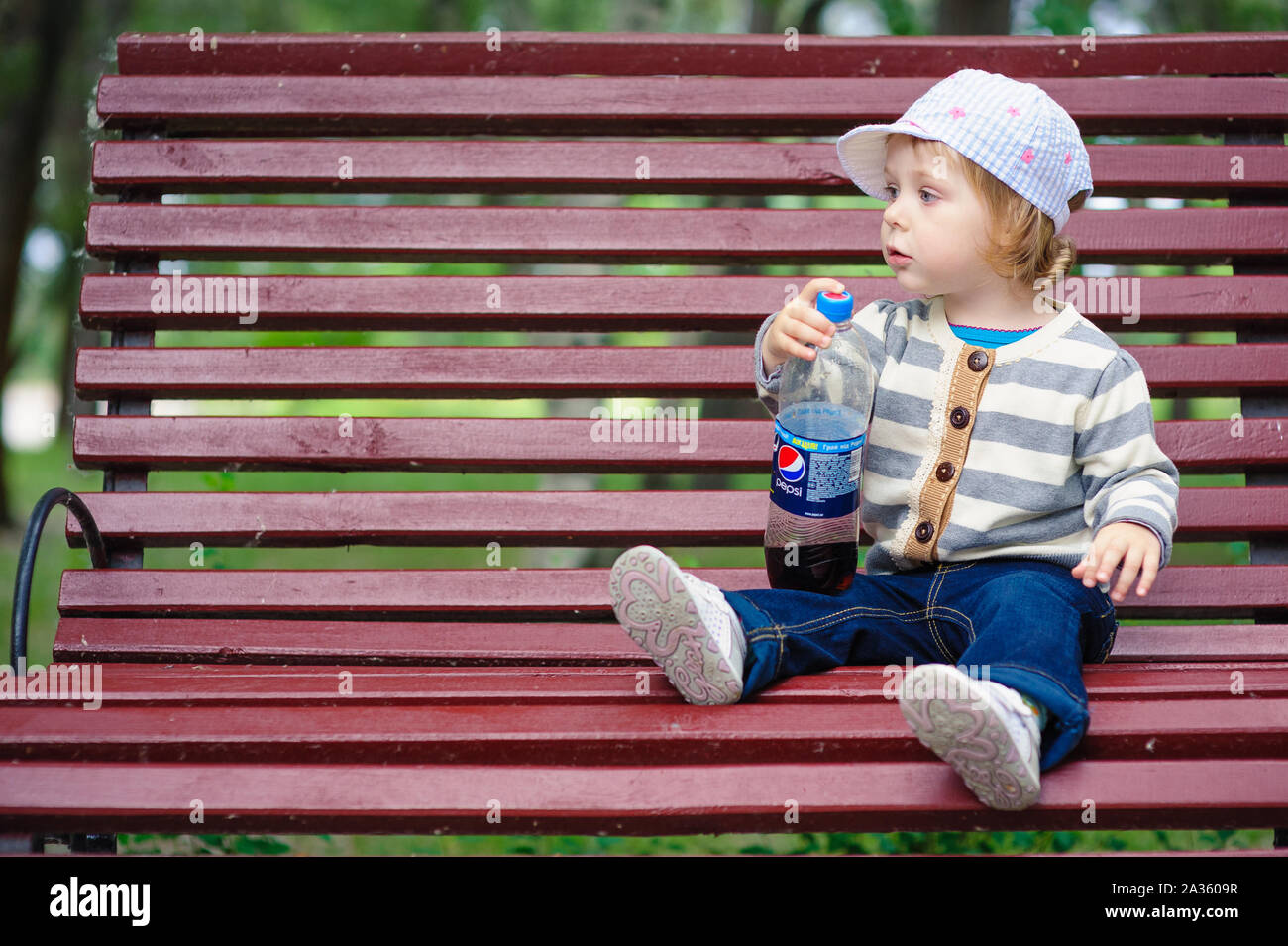 Small girl sitting on the bench in park Stock Photo - Alamy