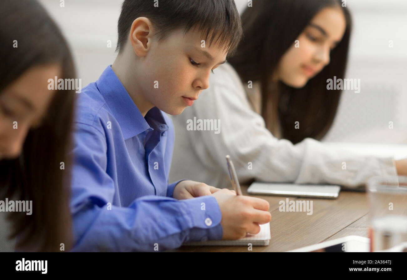 Children writing in copybooks during lesson in classroom Stock Photo ...
