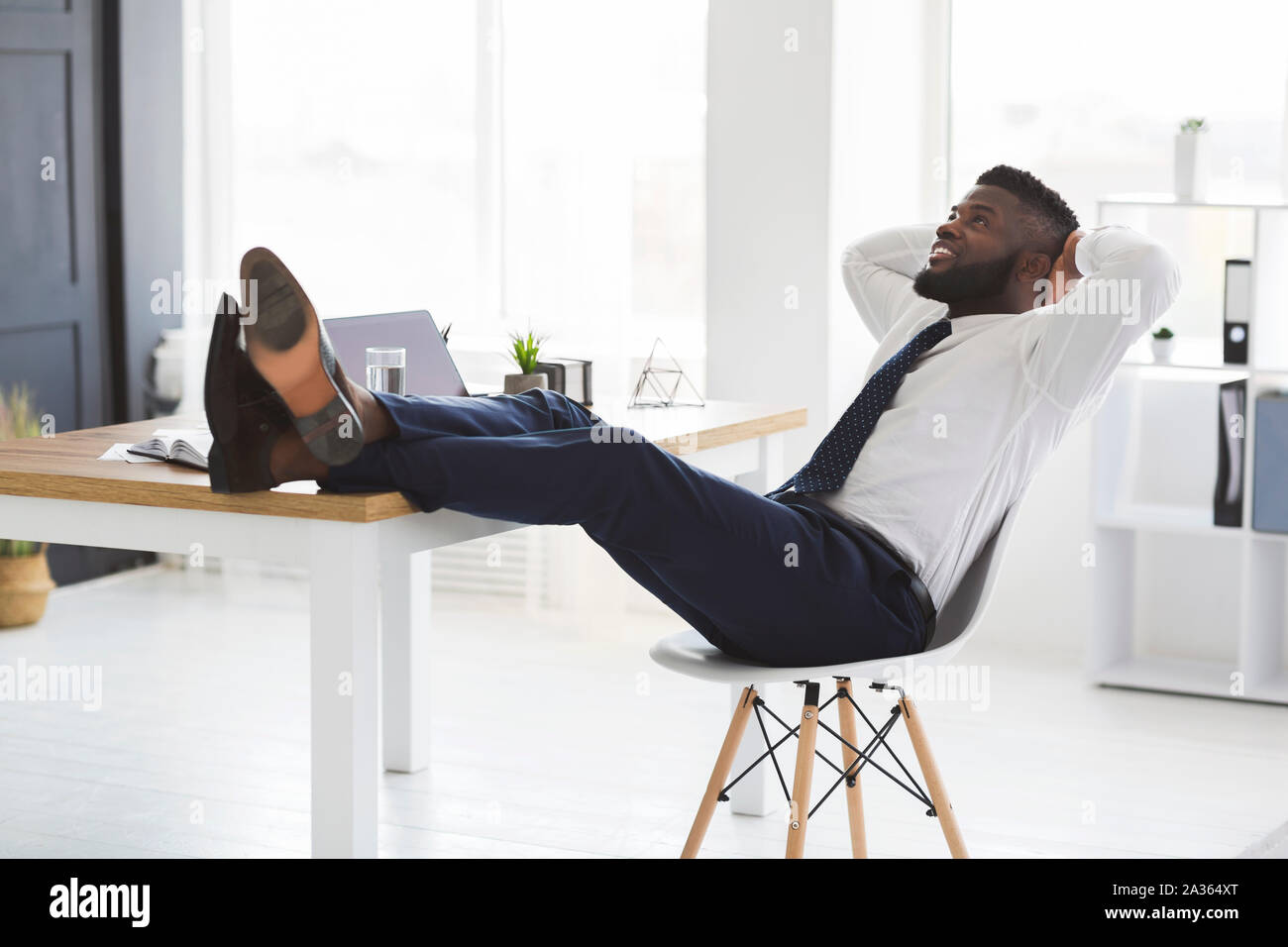 Joyful young manager relaxing on chair in white modern office Stock ...