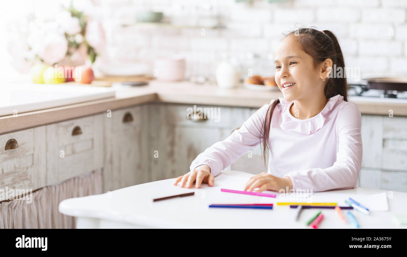 Adorable little girl sitting at kitchen table and smiling Stock Photo ...