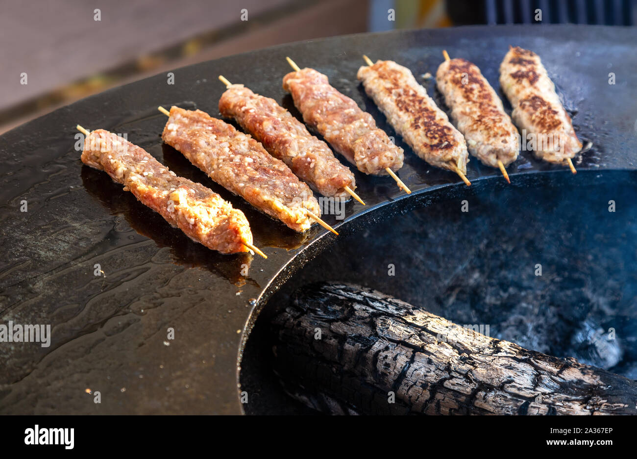 Grilled appetizing kebab cooking on wooden skewers. Shashlik made of ...