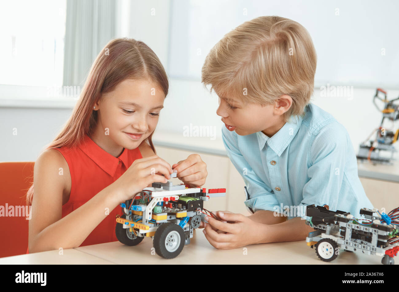 Robotics. Brother and sister having class sitting making robots ...