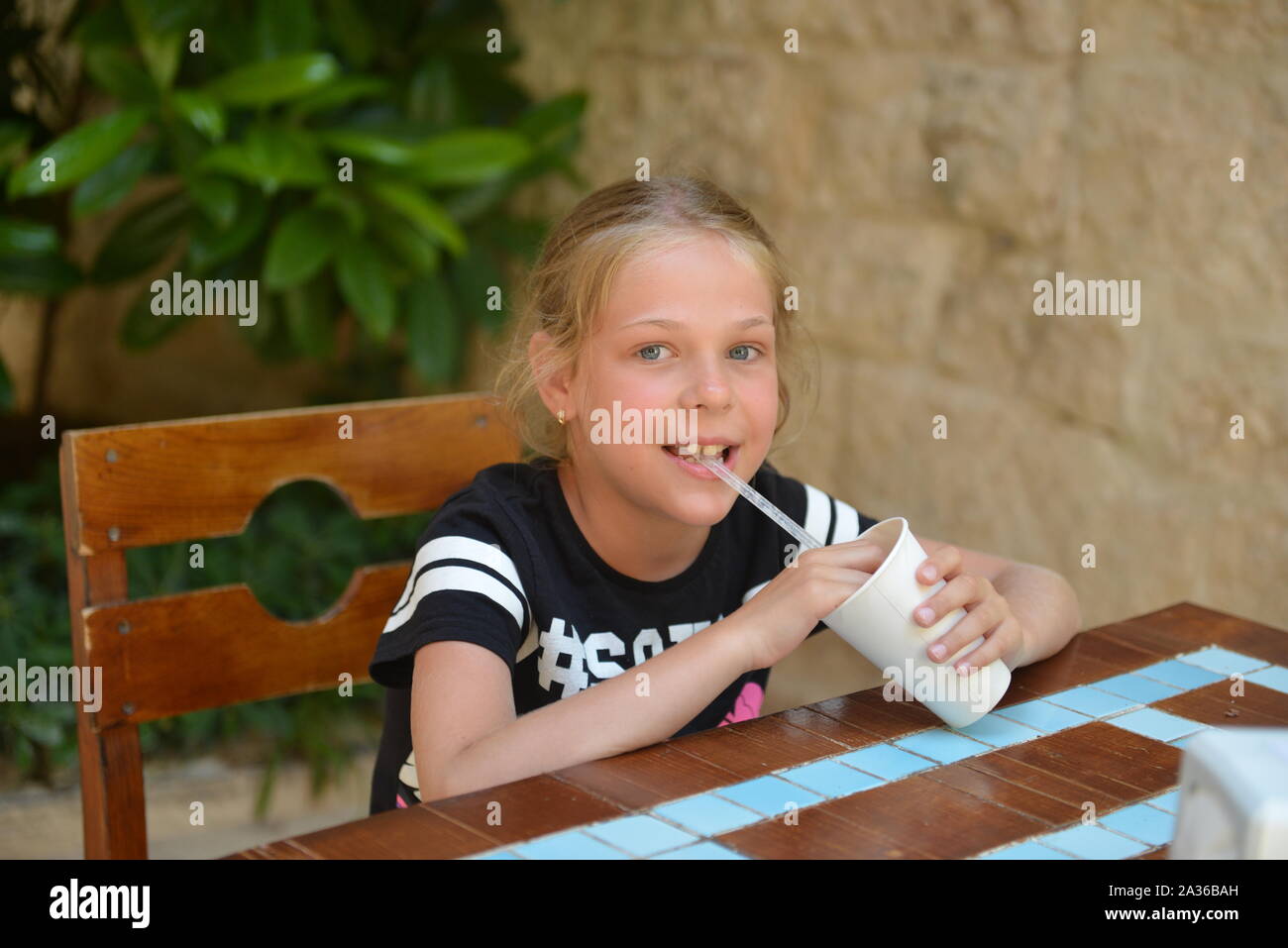Little girl drinks milk cocktail in a street cafe. Summer holiday Stock ...