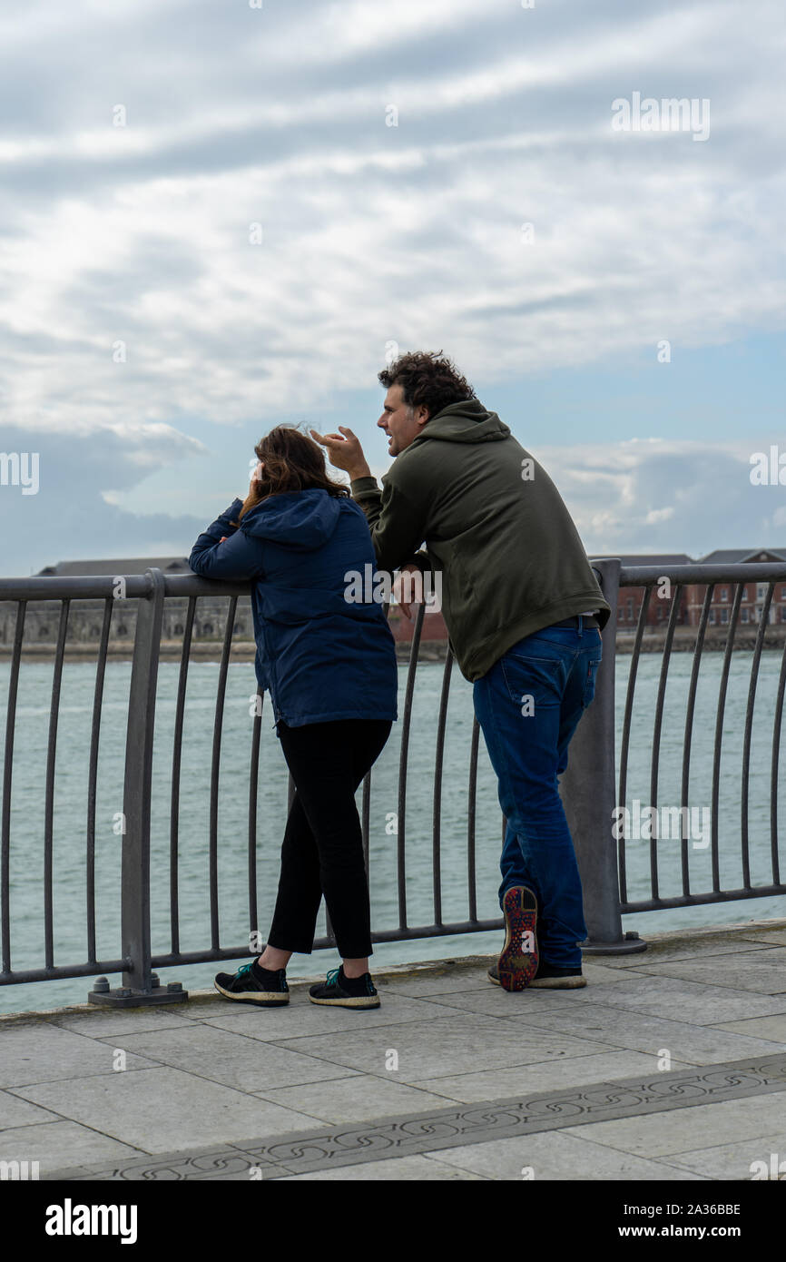 A couple talking while looking out to see leaning over railings Stock ...