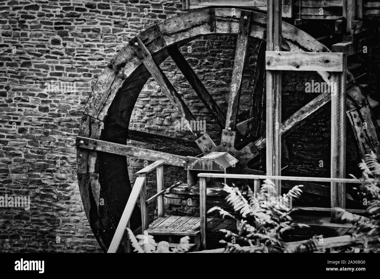 Old water mill wheel in front of stone wall. Black and white Stock ...