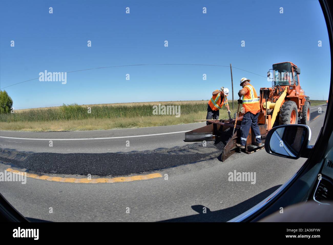 Road repair using front loader with paving machine attached by the ...