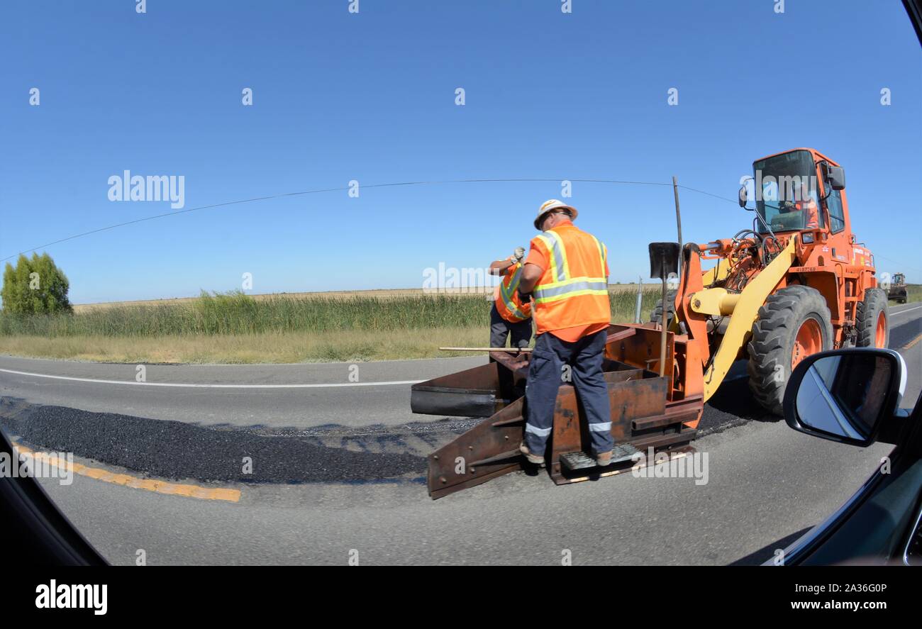 Road repair using front loader with paving machine attached by the ...