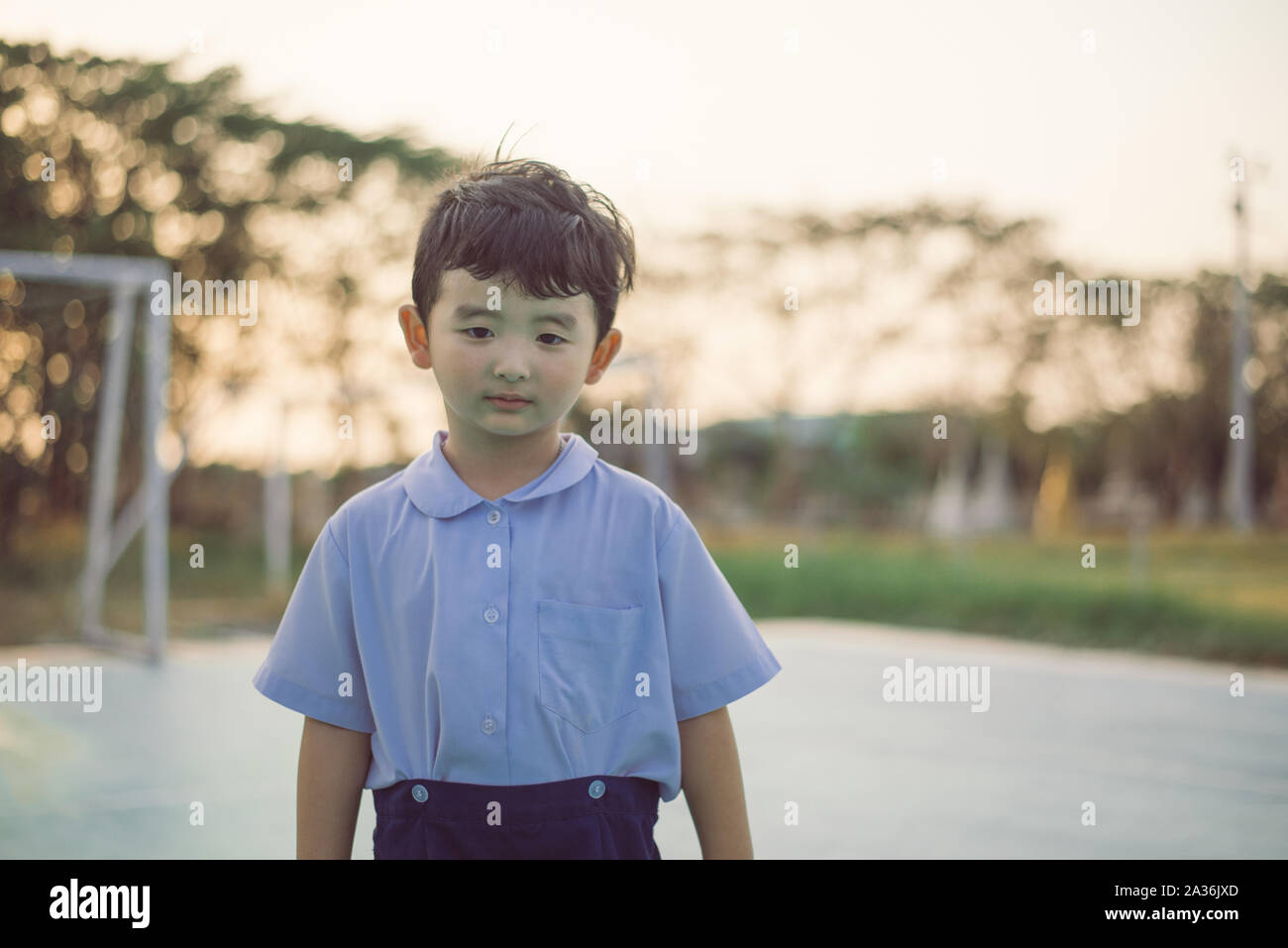 Outdoor portrait of a happy Asian student kid in school uniform smiling with copy space for add ...
