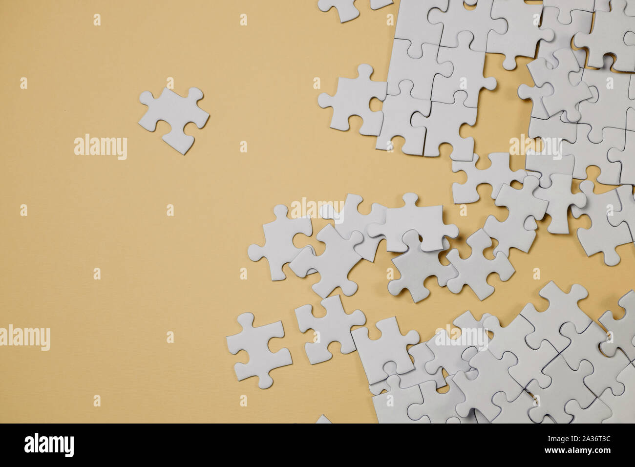 Fragment of a folded white jigsaw puzzle and a pile of uncombed puzzle ...