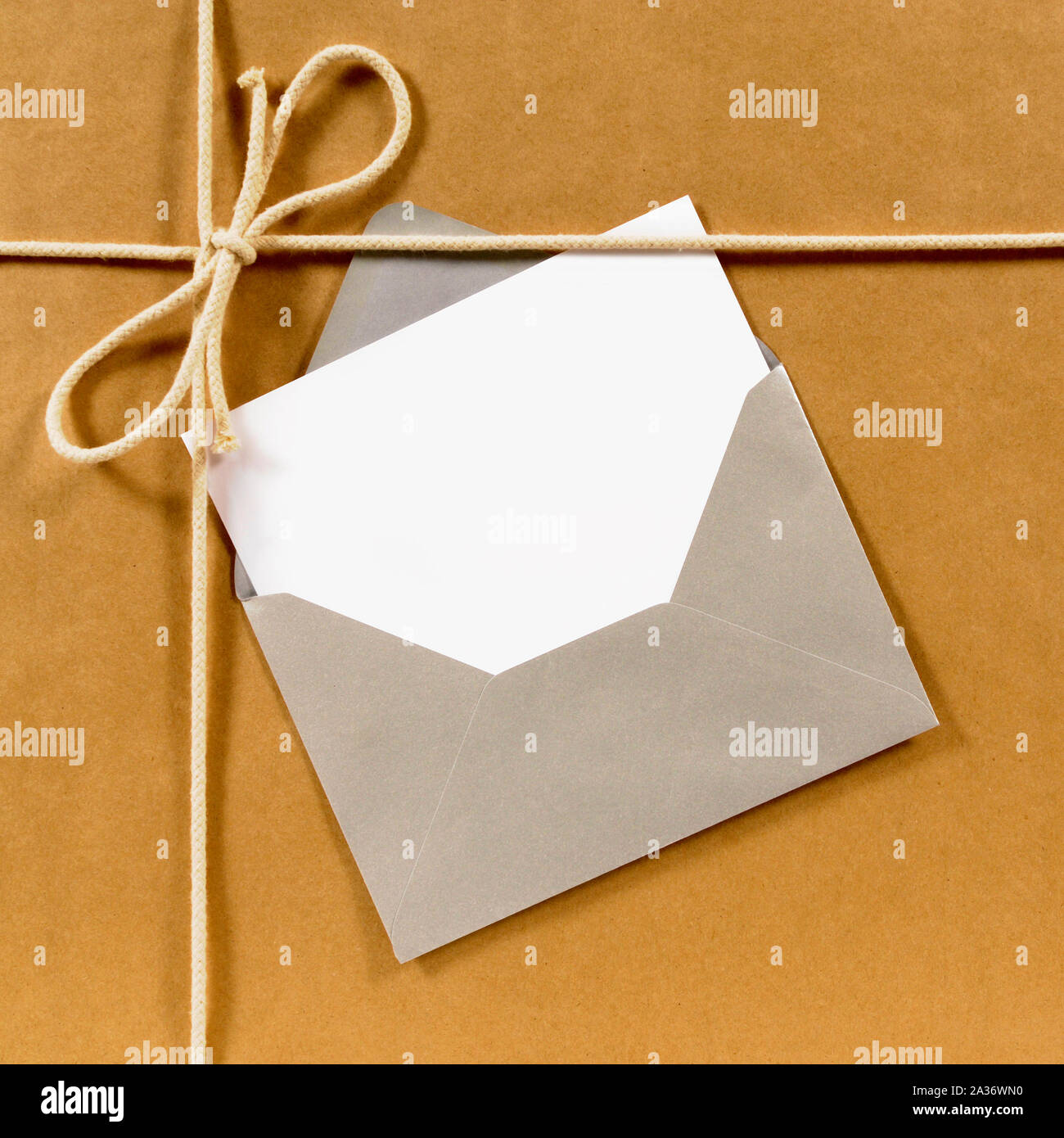 Brown paper parcel with silver envelope and blank message card Stock ...