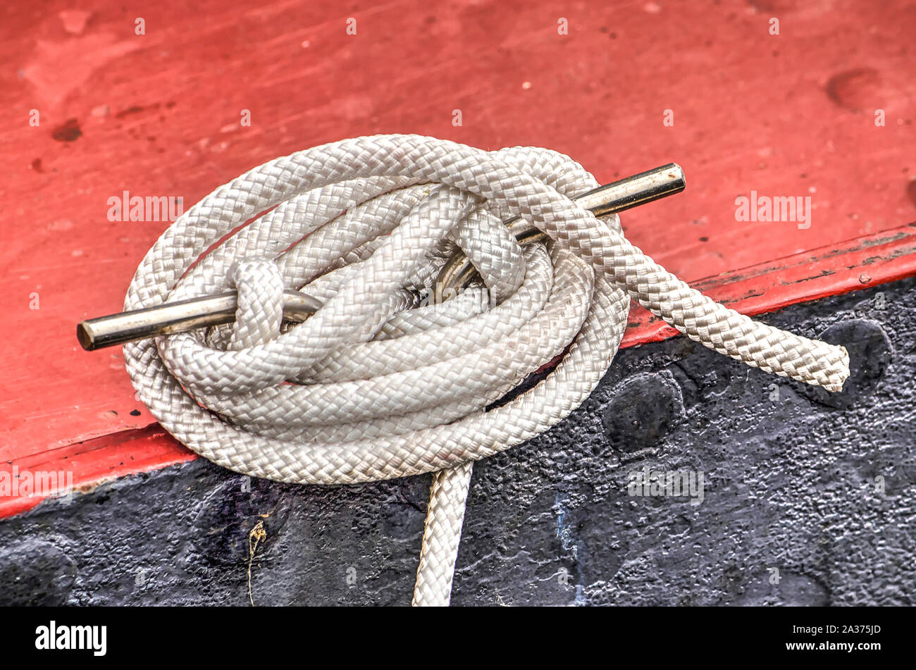 White marine rope tied in a nautical knot on the red and black steel ...