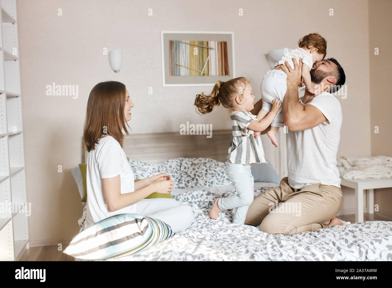 handsome kind daddy adores his daughters, kissing them in the bedroom ...