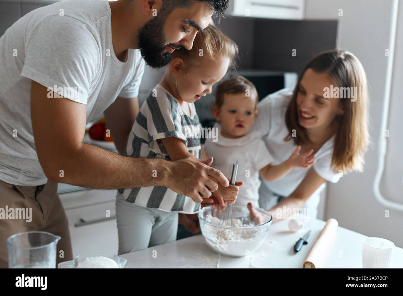 bearded daddy and smiling beautiful mother teaching their children to ...