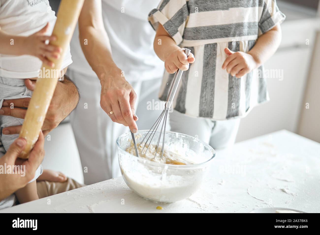 children mixing pastry in the kitchen, helping parents to bake a cake ...