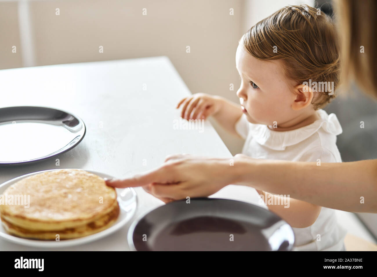 woman pointing to pancakes, asking the kid to taste them. close up ...