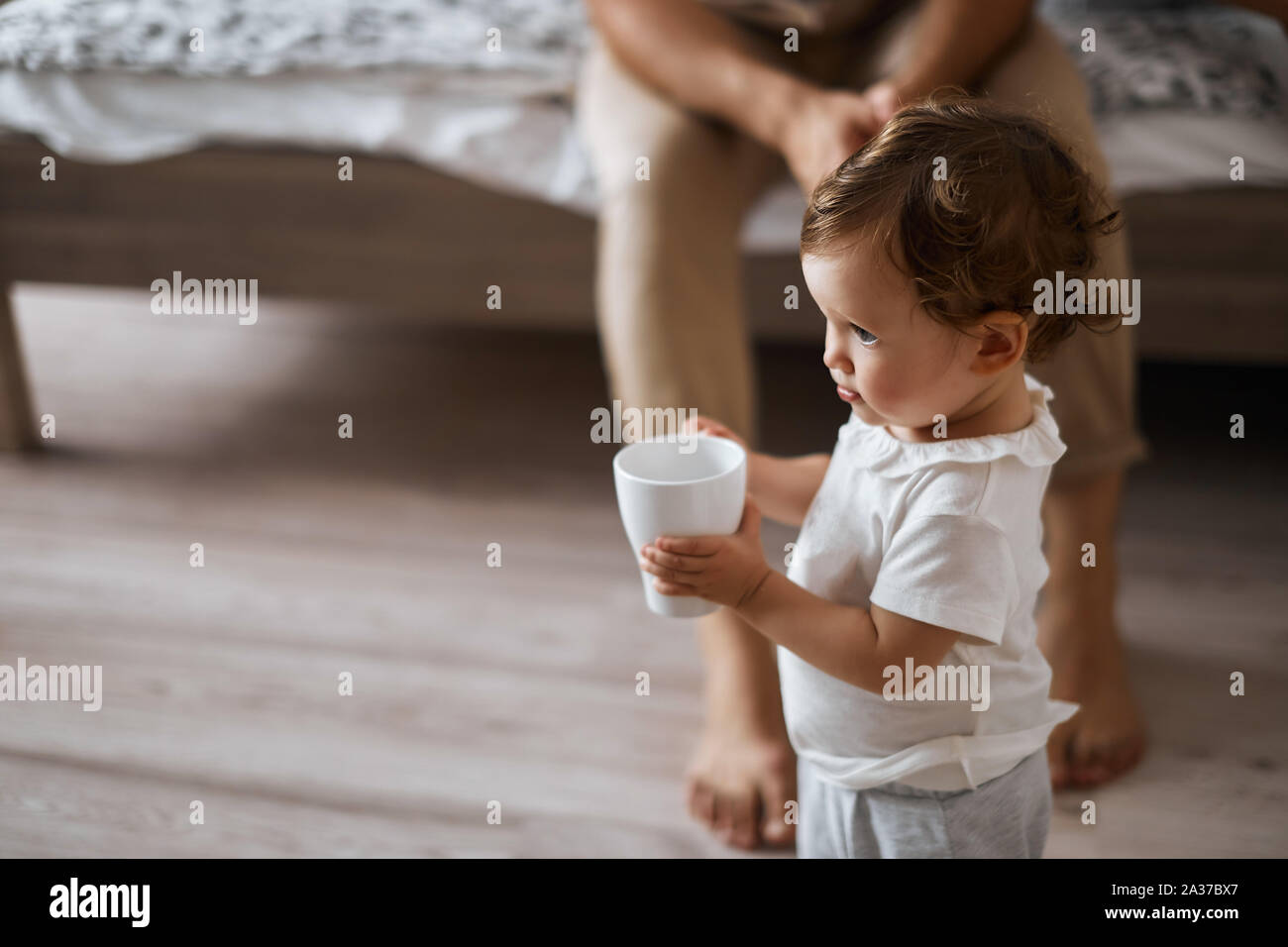 little adorable girl with a cup walking at home. mother's helper. close ...