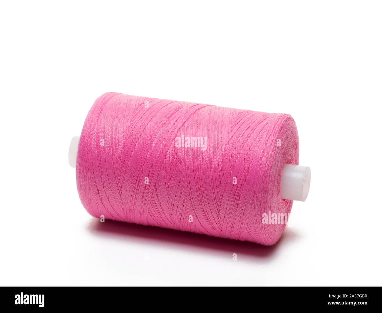 Pink spool of thread in a horizontal position on a white background ...