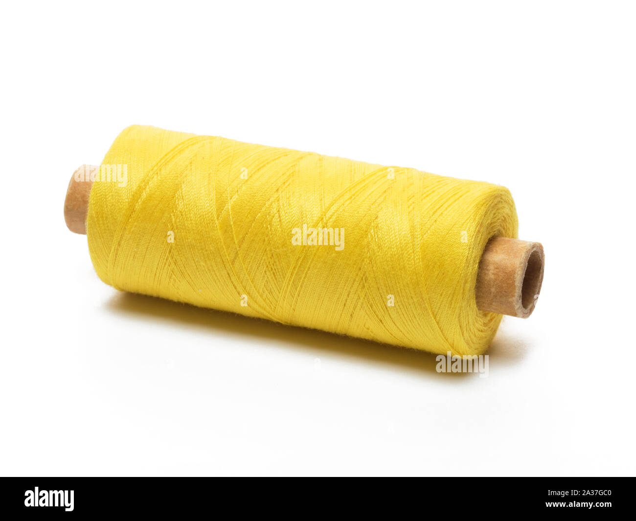 Yellow spool of thread in a horizontal position on a white background ...