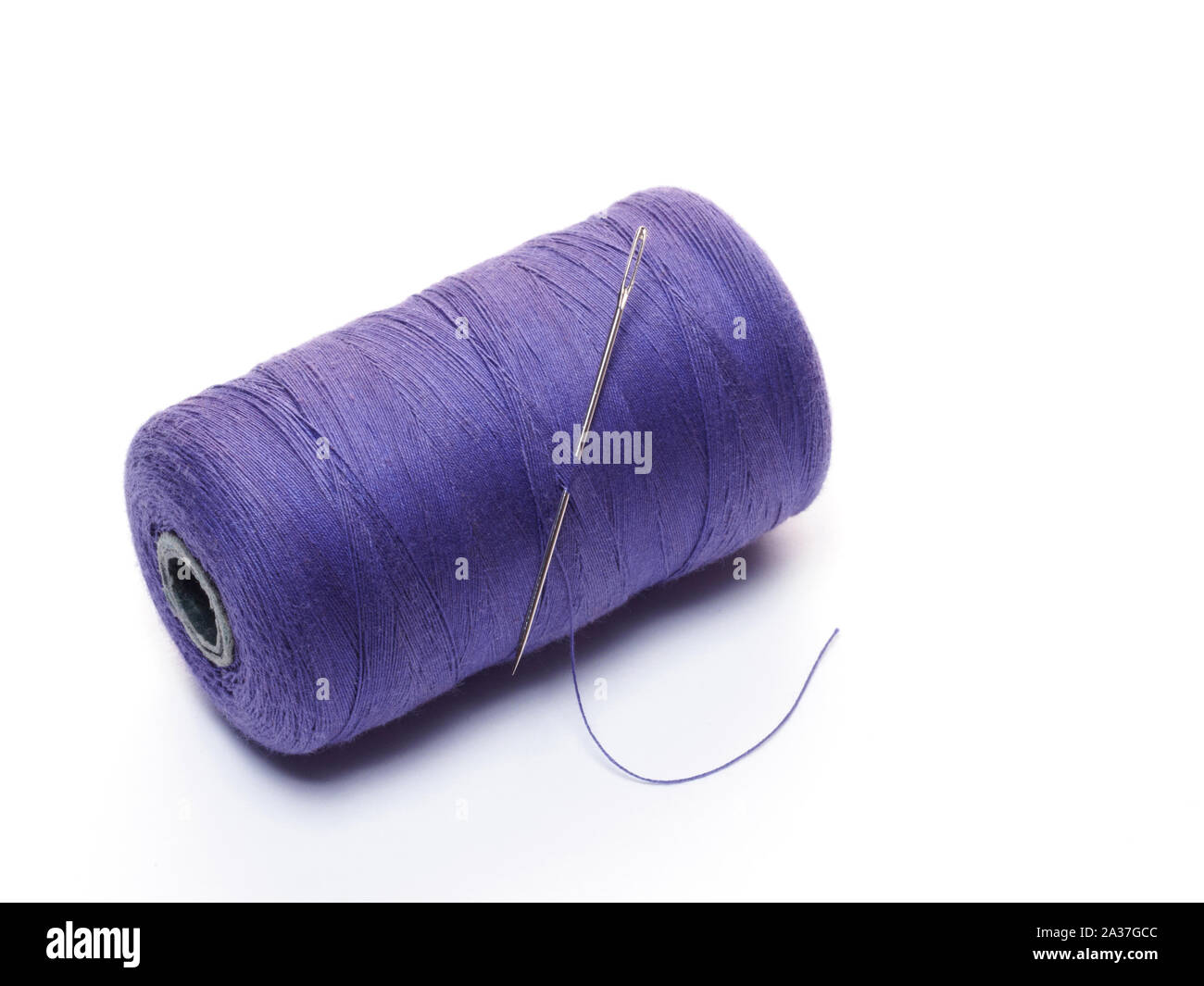Blue spool of thread in a horizontal position with a needle on a white ...