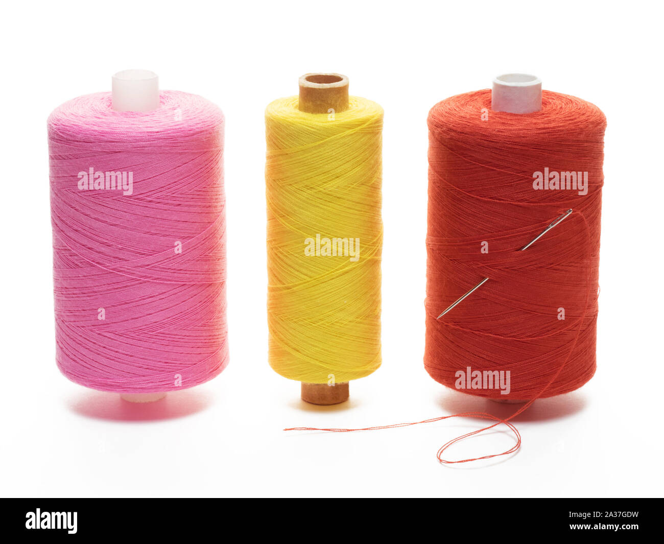 Three coils, yellow, red and pink threads in a vertical position with a ...