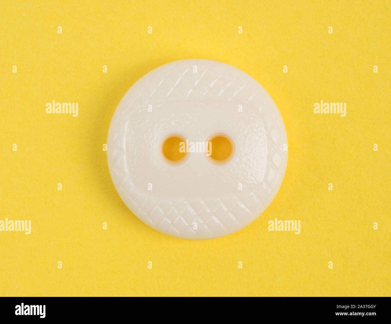 White plastic button on yellow background Stock Photo - Alamy