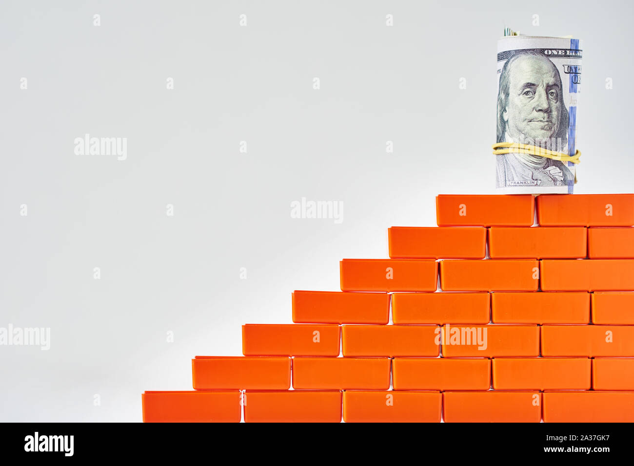 dollar bill on top of wall made of toy bricks on white background ...