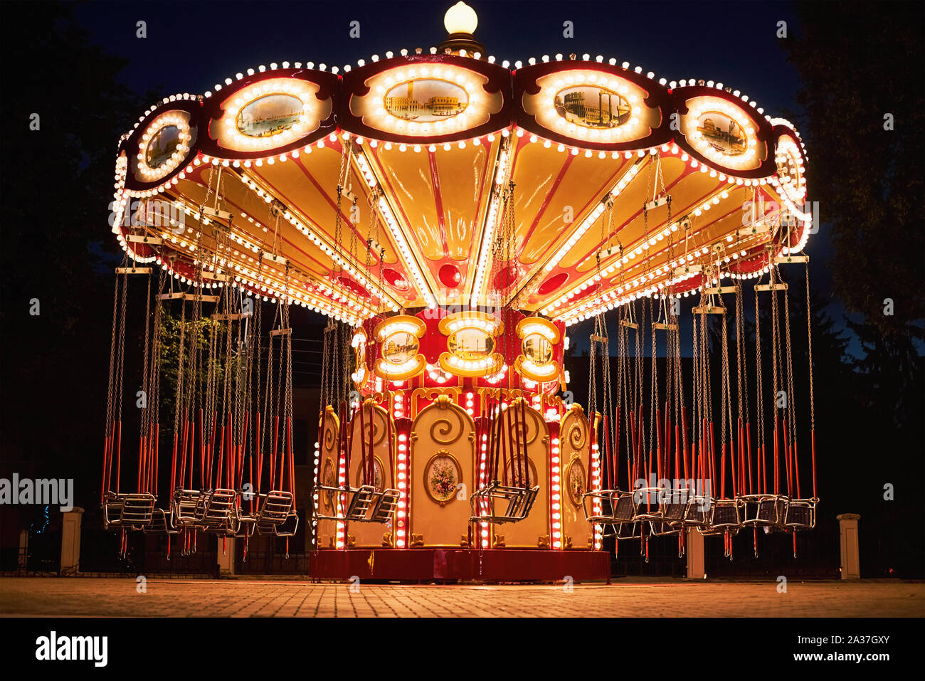 Illuminated swing chain carousel in amusement park at night Stock Photo ...