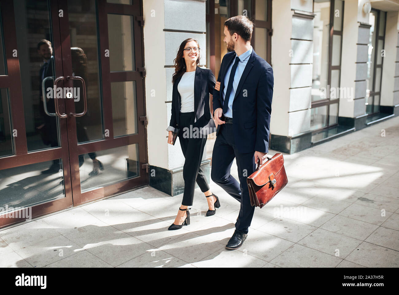 positive office workers walking in the modern city, enjoying companym ...