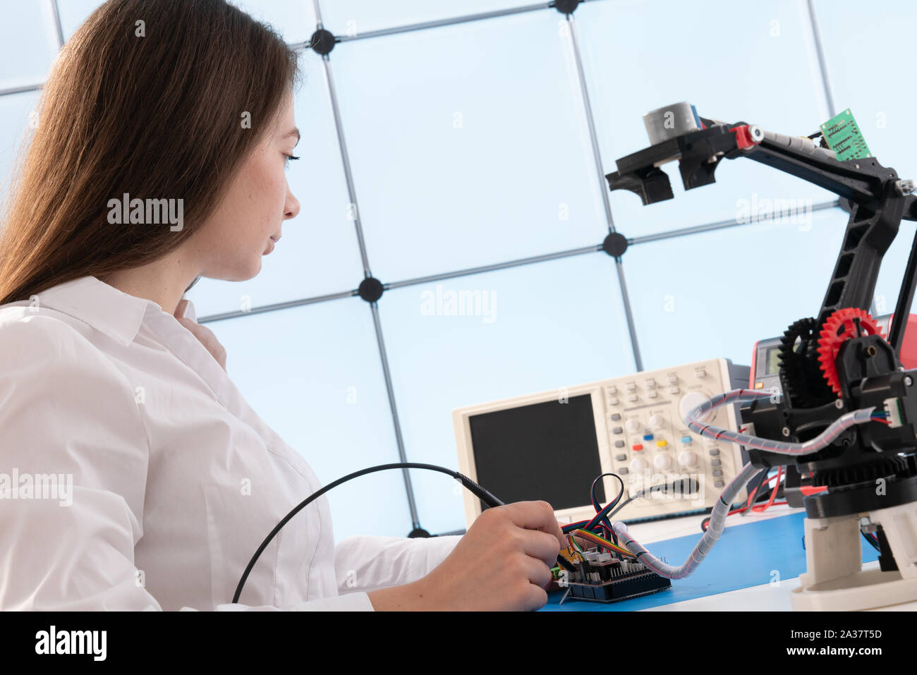 A young woman writes an algorithm for the robot arm. Science Research ...