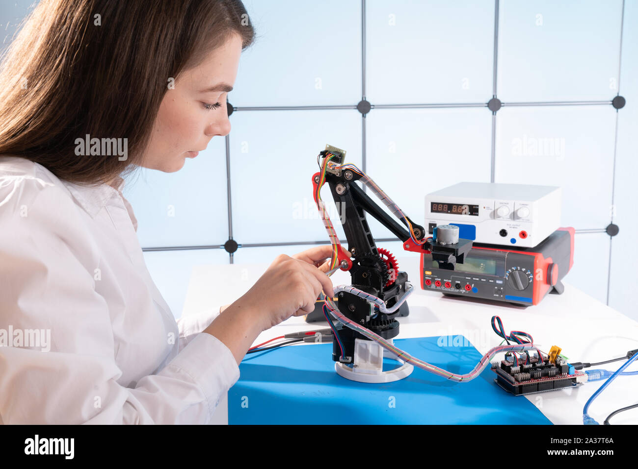 A young woman writes an algorithm for the robot arm. Science Research ...