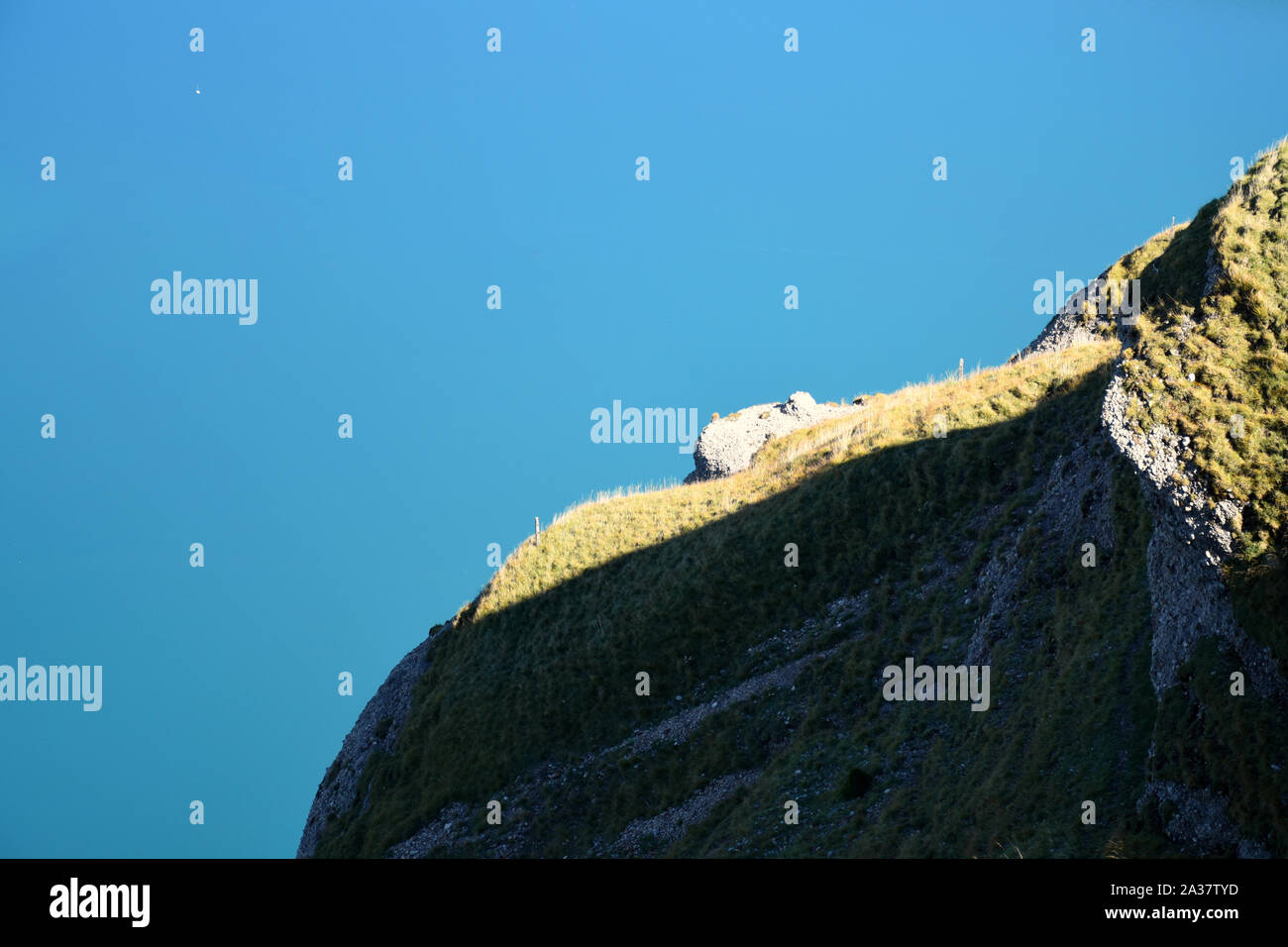 An oval shaped rock viewpoint on a hillside in the sun with Lake Zug in ...