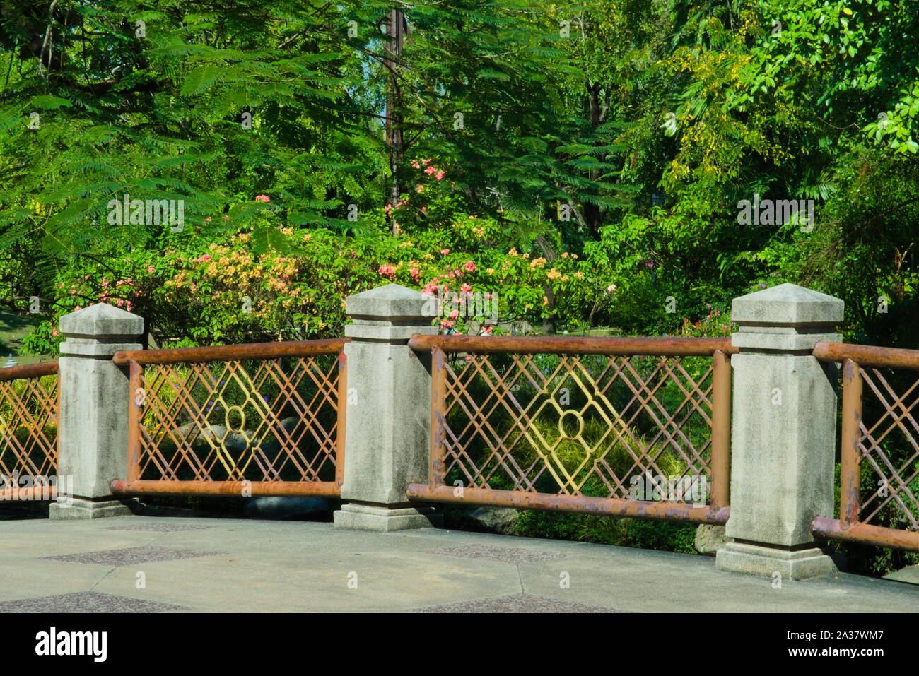 A lovely bridge with steel railing, in a lush garden park, crossing a ...