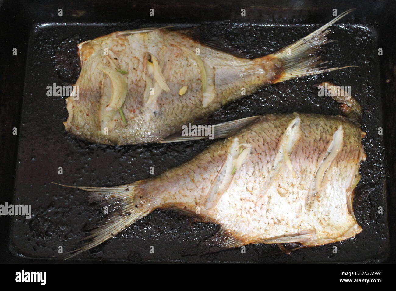two fish baked and lay on pan prepare for dinner Stock Photo - Alamy