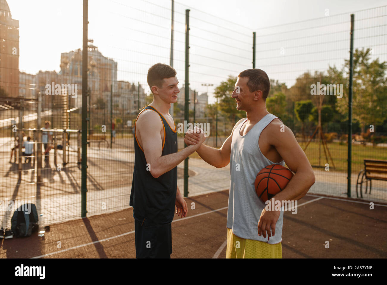 Two basketball players shake hands, outdoor court Stock Photo - Alamy