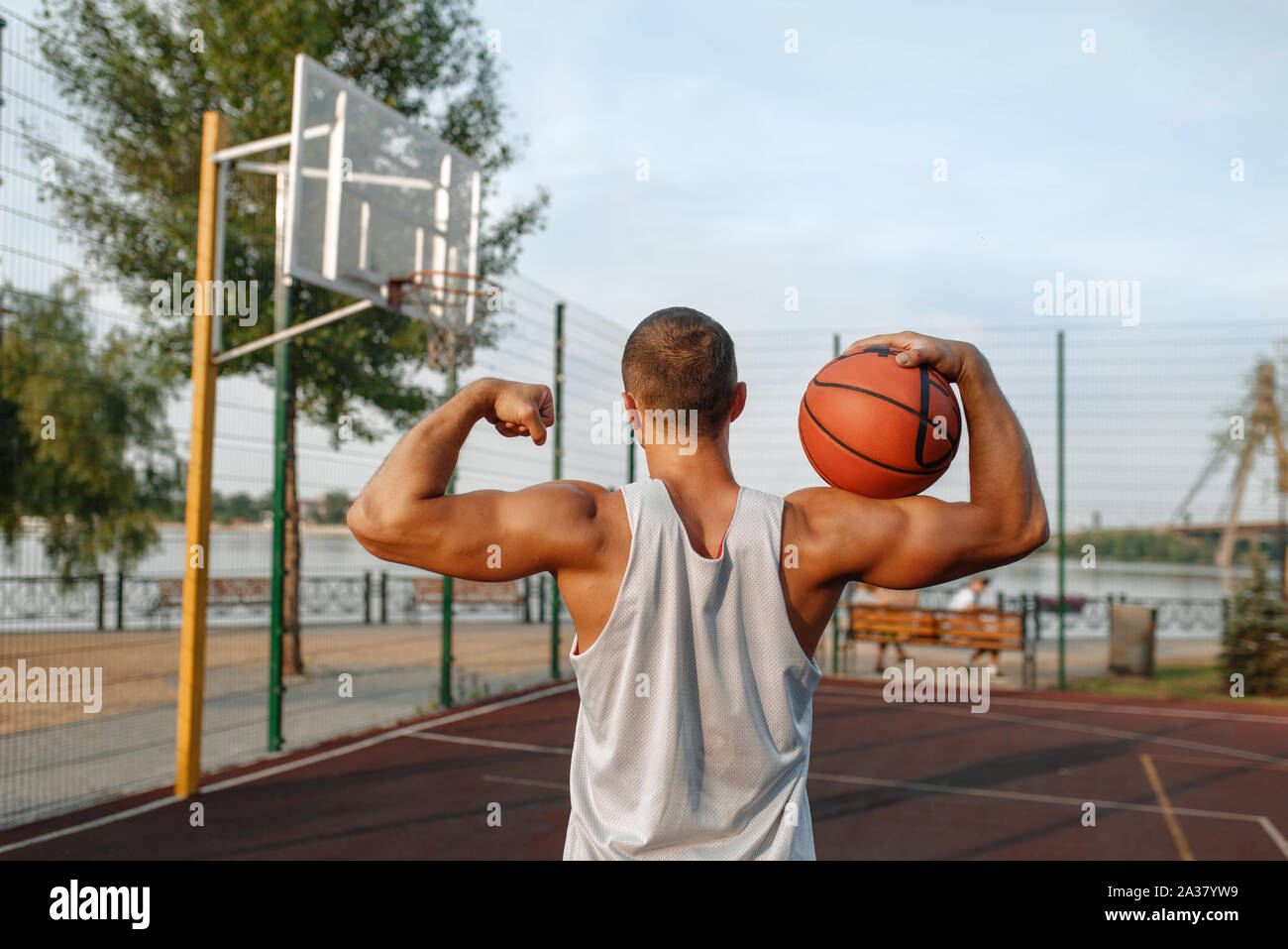 Male basketball player with ball shows his muscles Stock Photo - Alamy