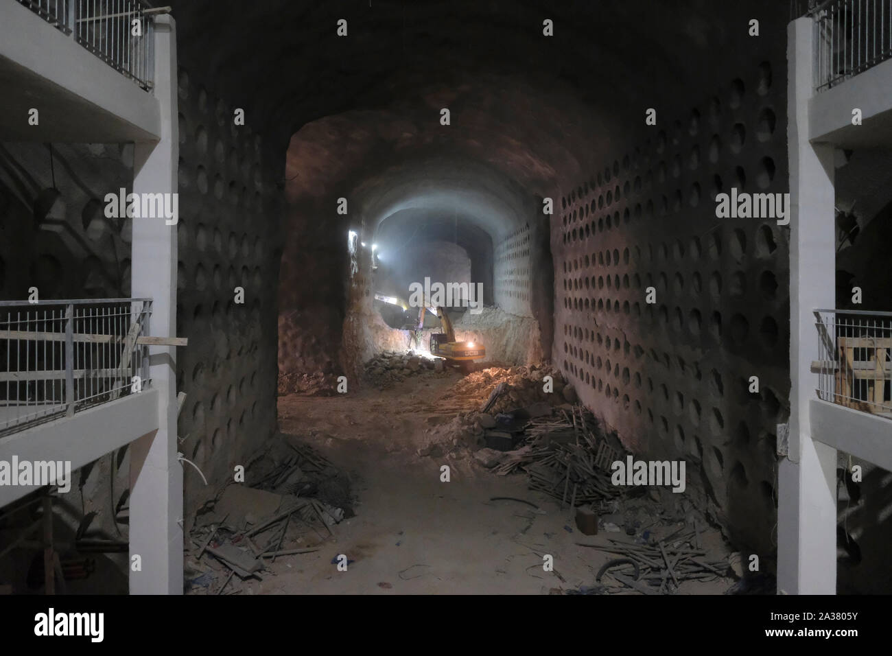 A crawler excavator digging at the new massive underground burial ...