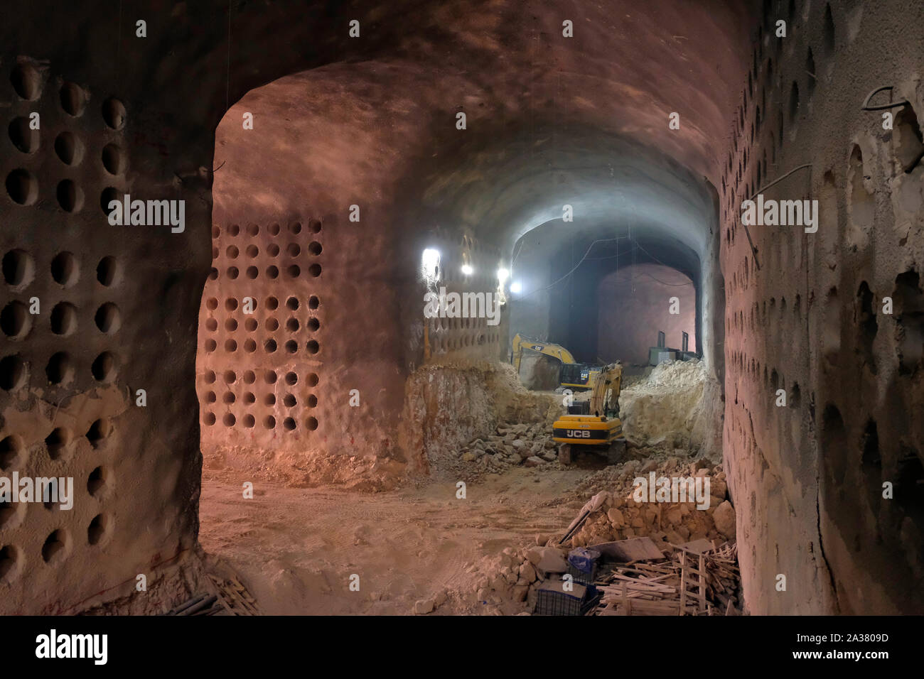 A crawler excavator digging at the new massive underground burial ...