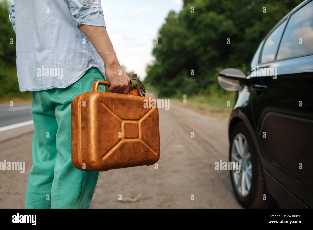 Man holds canister, car breakdown, out of gas Stock Photo - Alamy