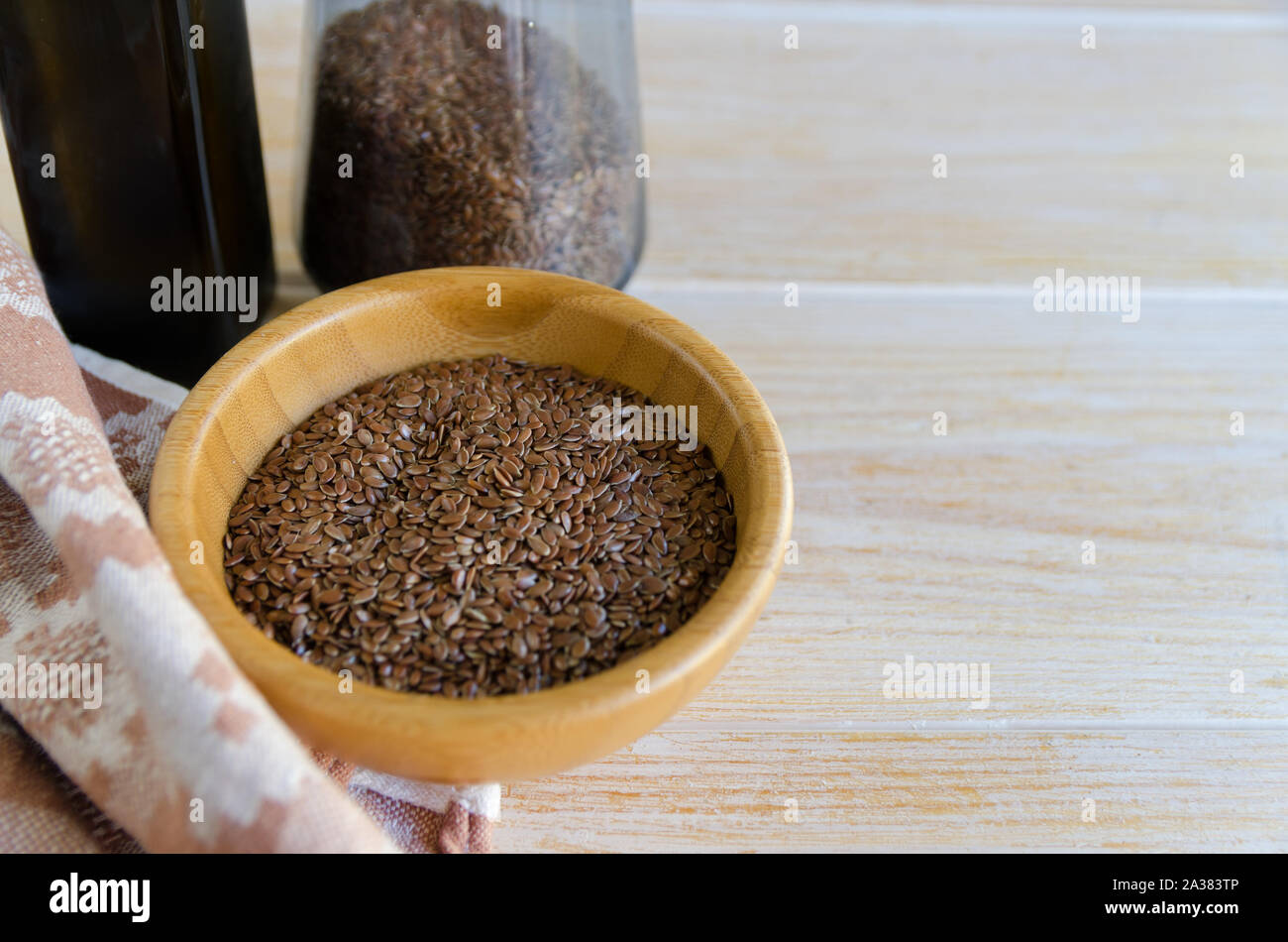 Brown flax seeds in wooden bowl and flaxseed oil on a rustic table. Superfood linseeds ...