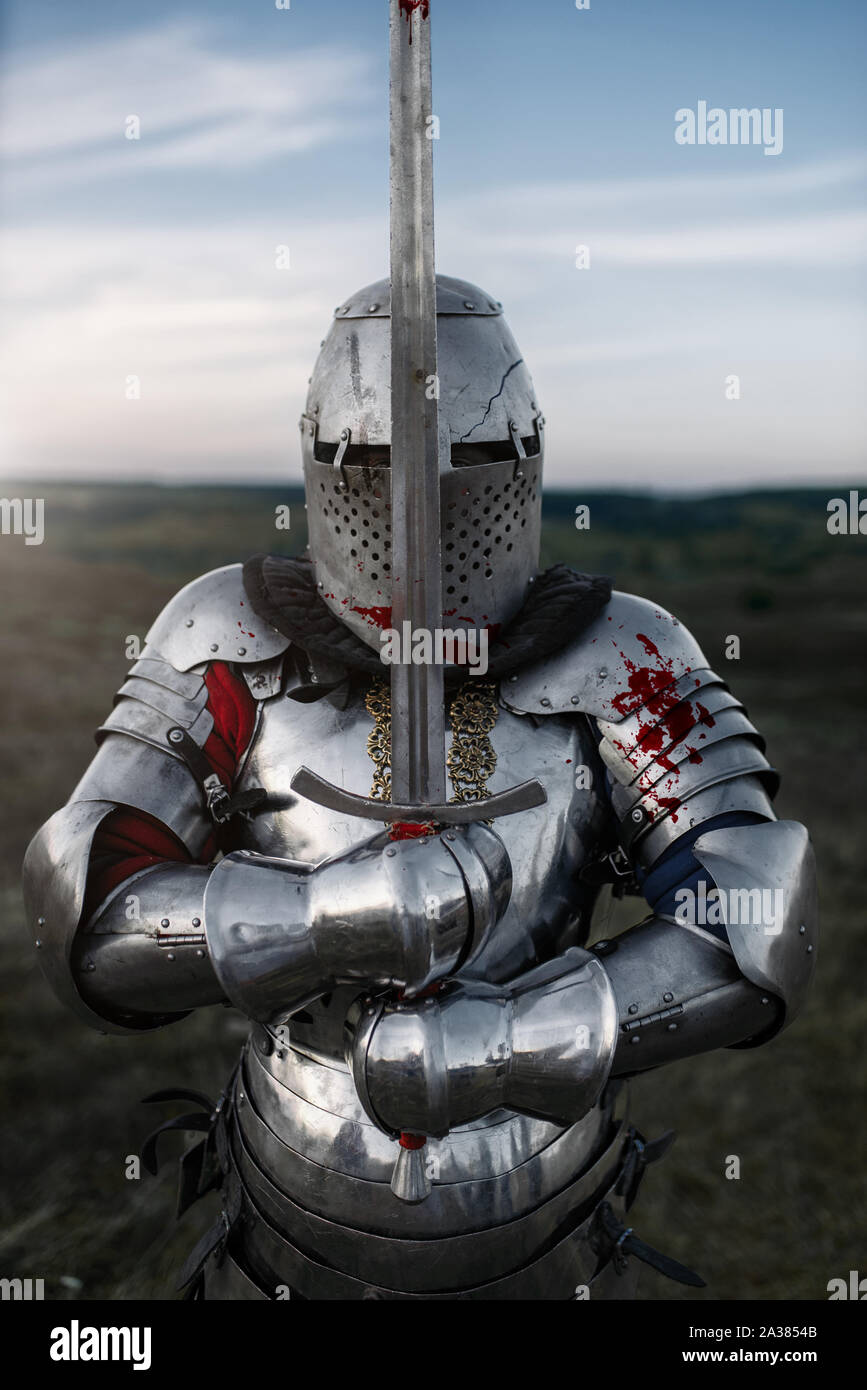 Knight in armor and helmet poses with sword Stock Photo - Alamy
