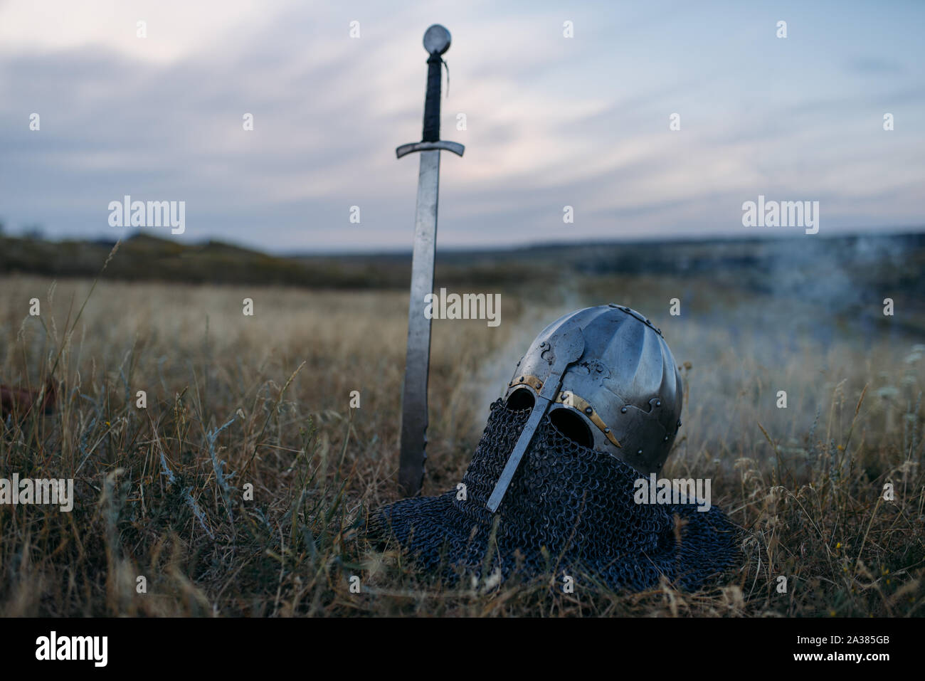 Sword stuck in the ground and metal knight helmet Stock Photo - Alamy