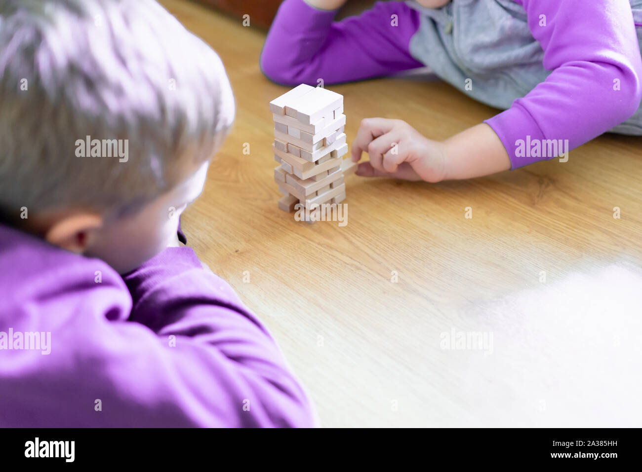 Children in purple is playing jenga, a wood blocks tower game for ...