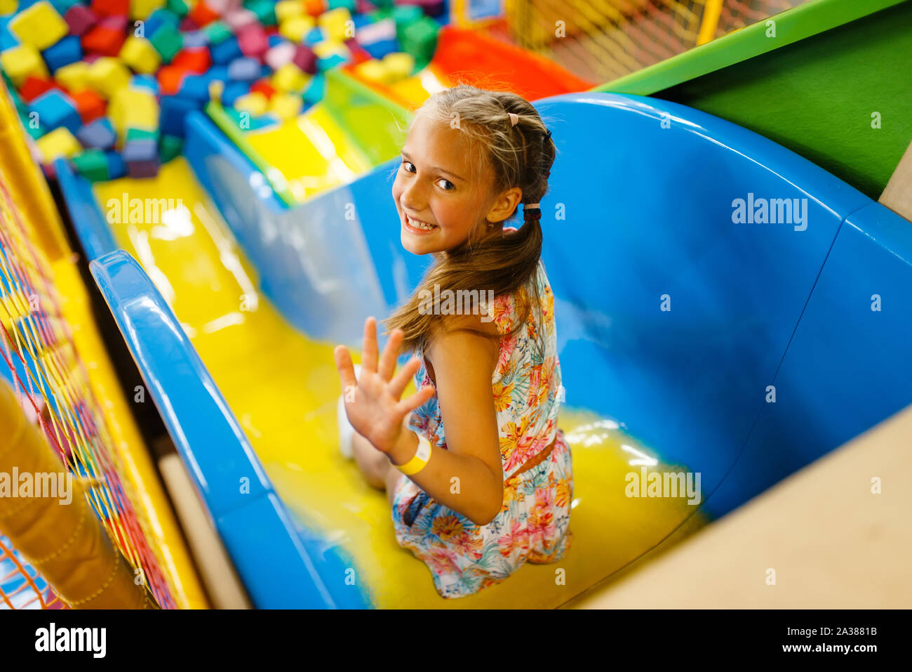 Little girl riding on plastic kids slide, playroom Stock Photo - Alamy