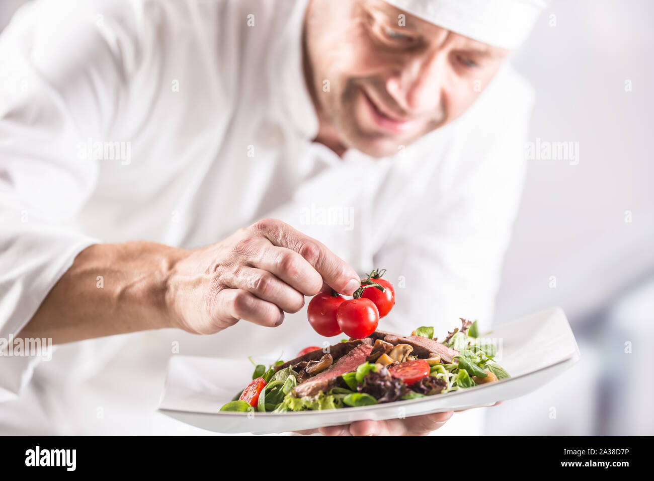 Chef in the kitchen of the hotel or restaurant decorates the food just ...