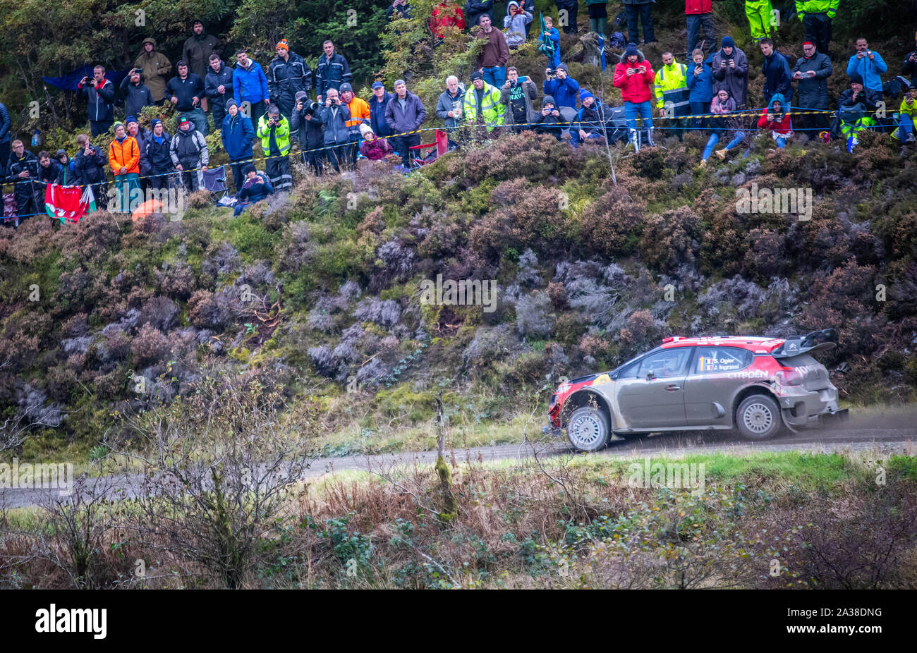 Spectators watch a World Rally Car pass through a gravel forest stage ...