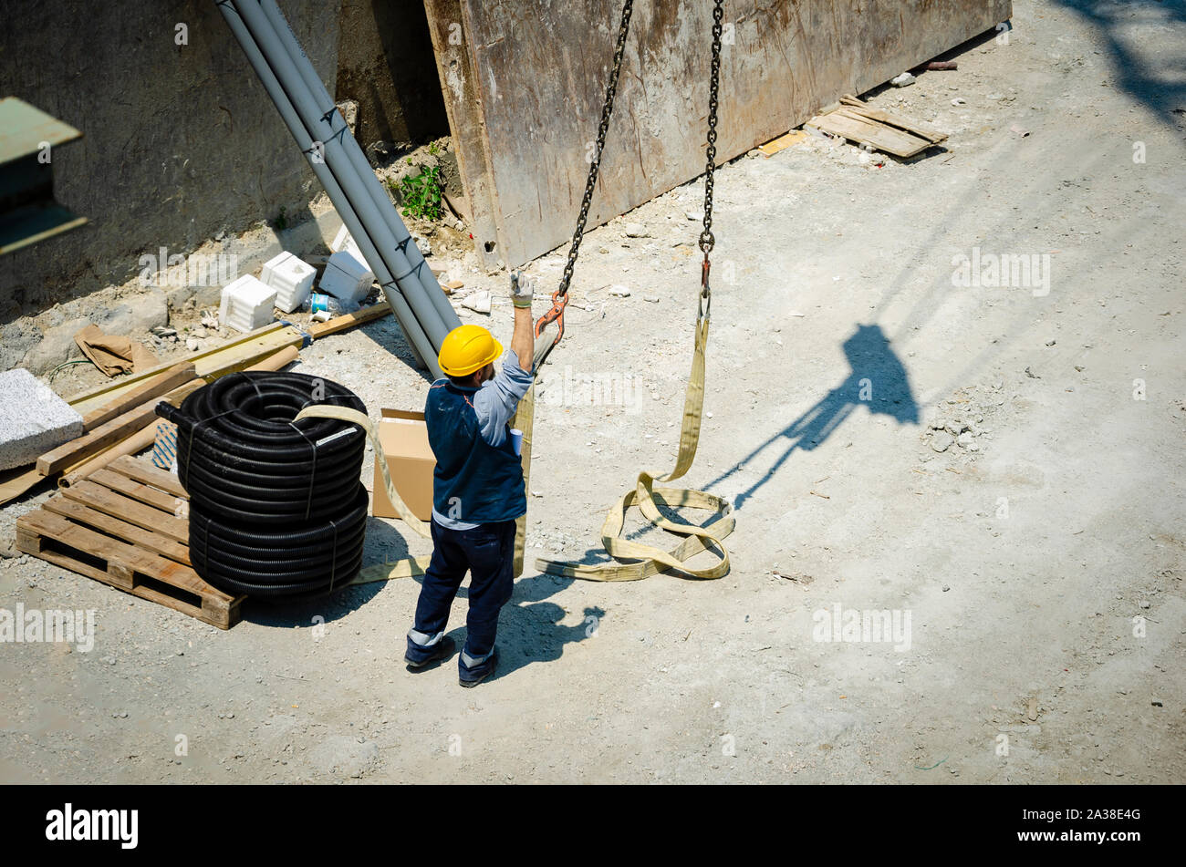 A worker man in helmet is ready to hang a Drain or corrugated pipe to ...